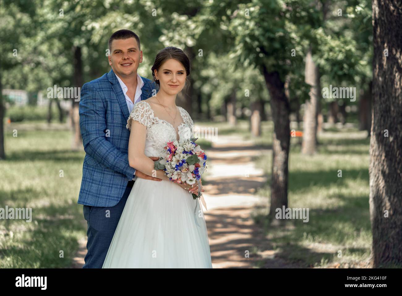 bride and groom stand in the park under a tree Stock Photo - Alamy