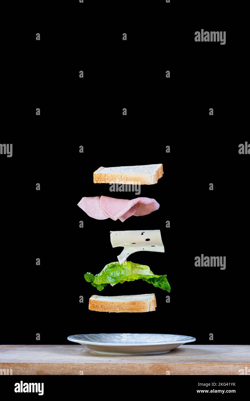 A floating sandwich with cheese, cooked ham, lettuce and sliced bread ...