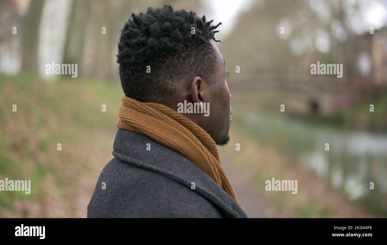 Pensive black man standing outside in cold winter season wearing scar ...