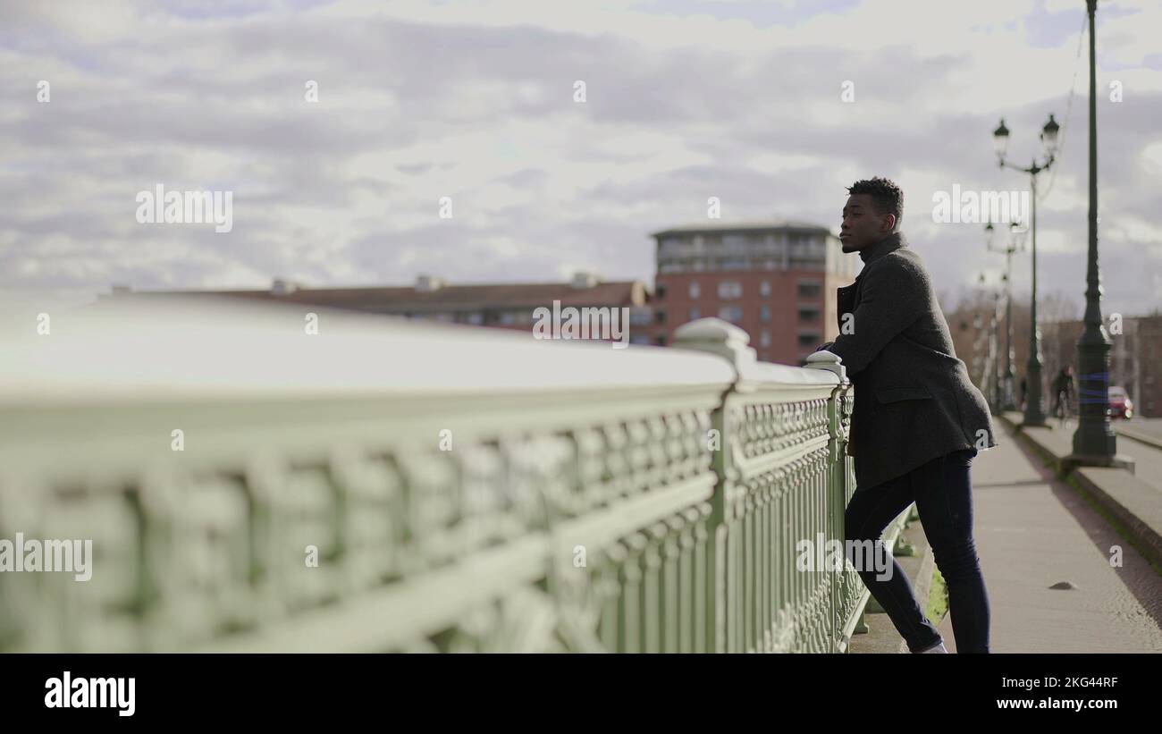 Pensive black man thinking about life on top of city bridge. Elegant ...