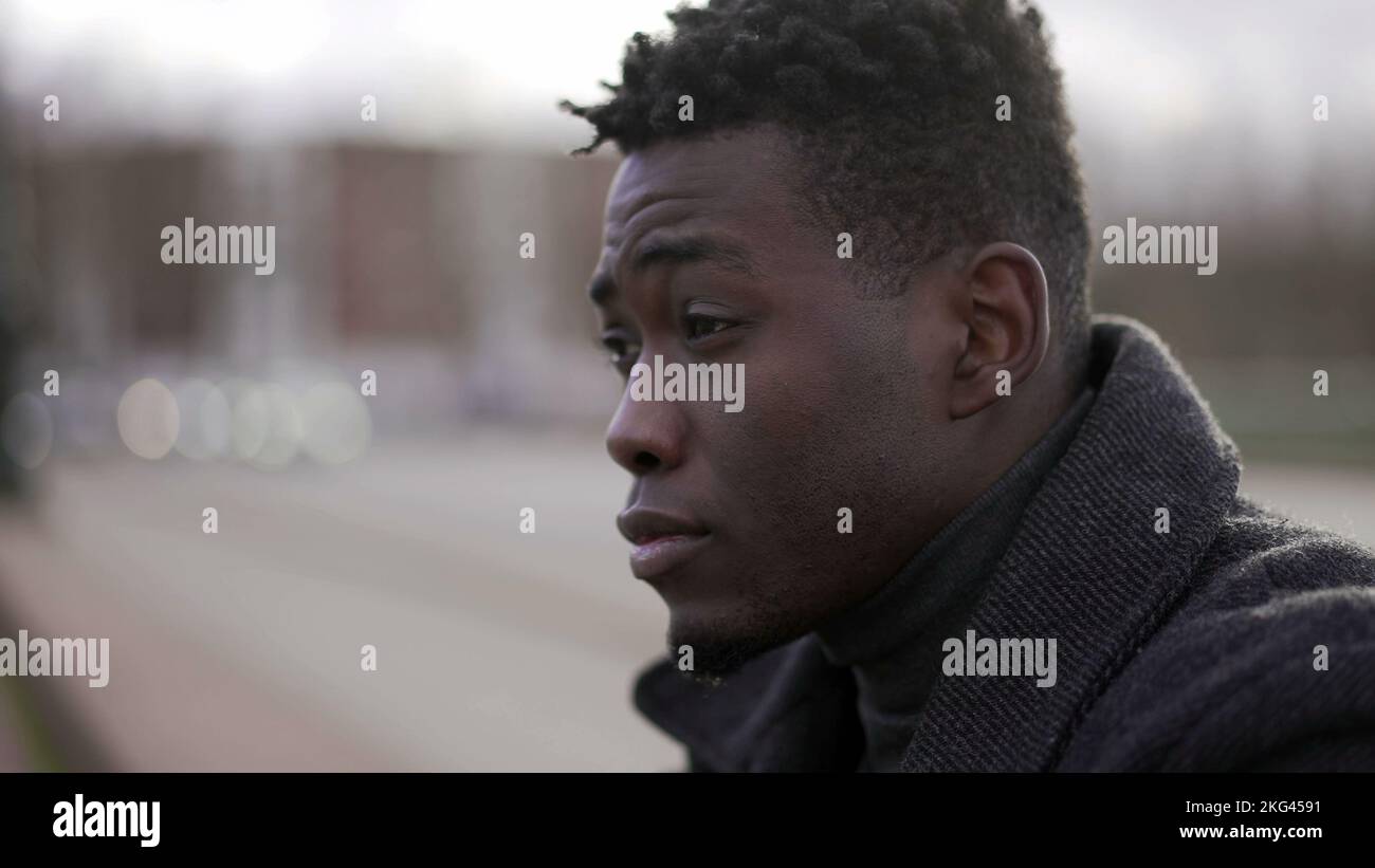 Pensive concerned black African man sitting on city sidewalk curb ...