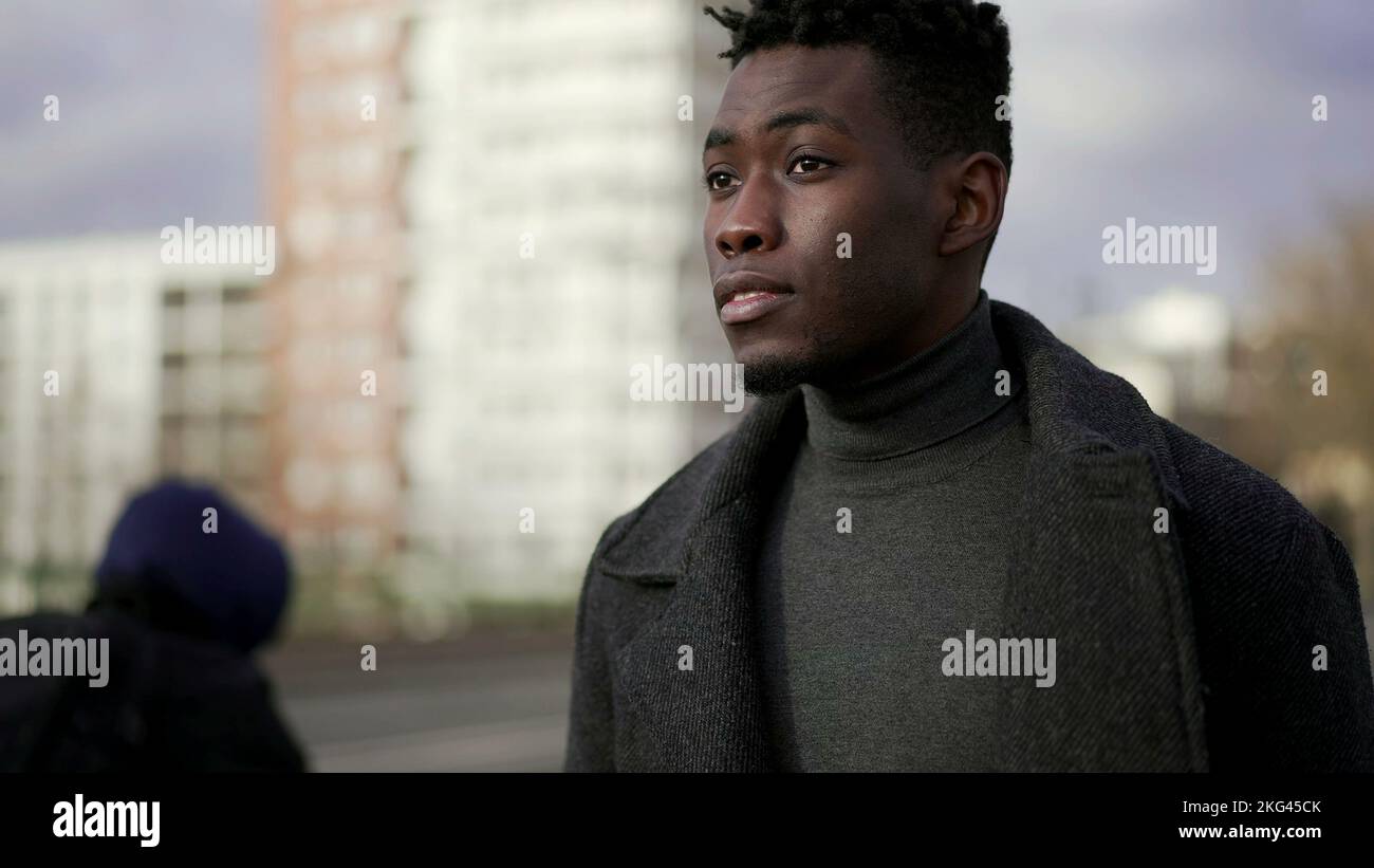 Pensive elegant black African man walking outside in city thinking ...
