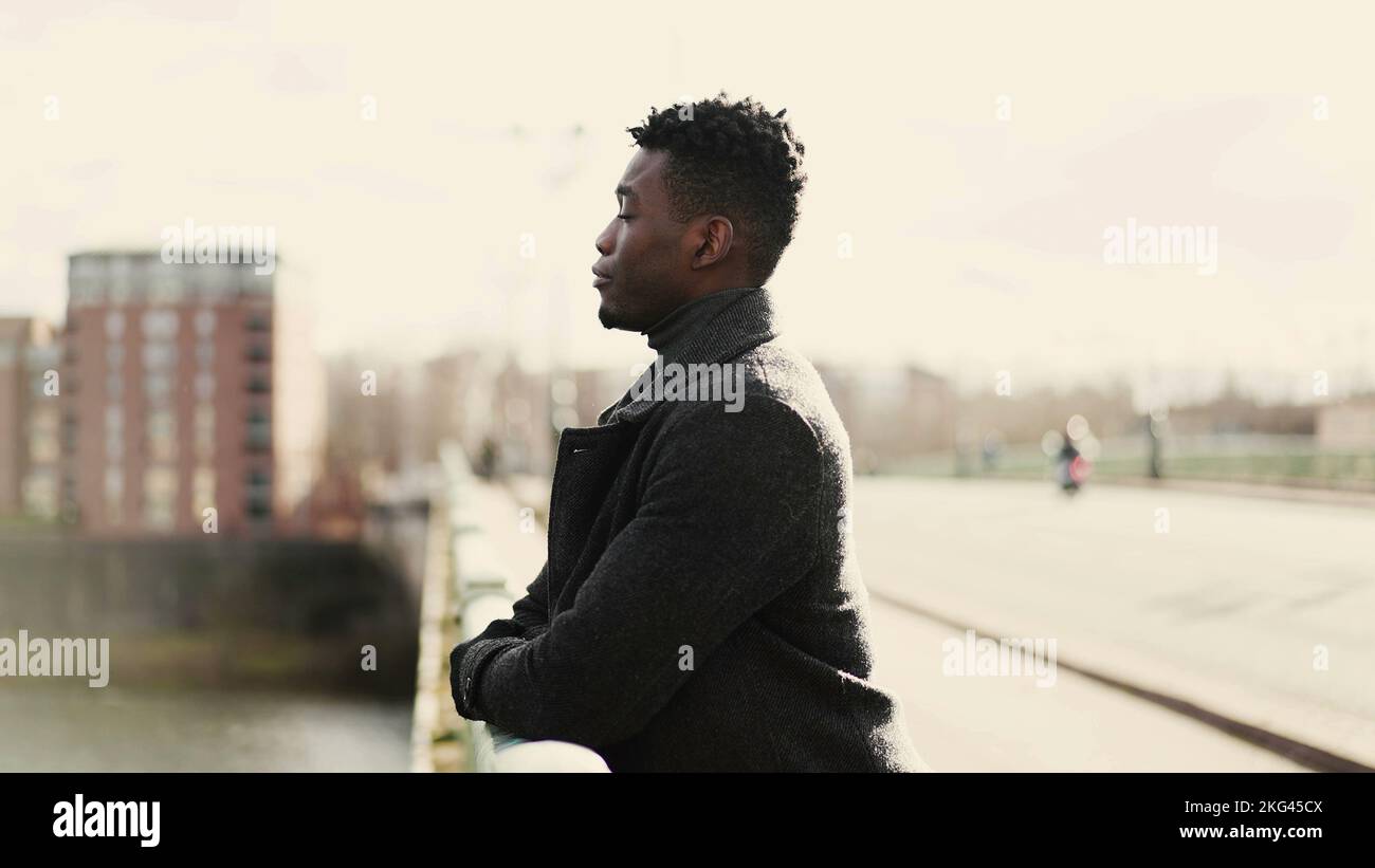 Pensive black African man standing by bridge thinking about life ...