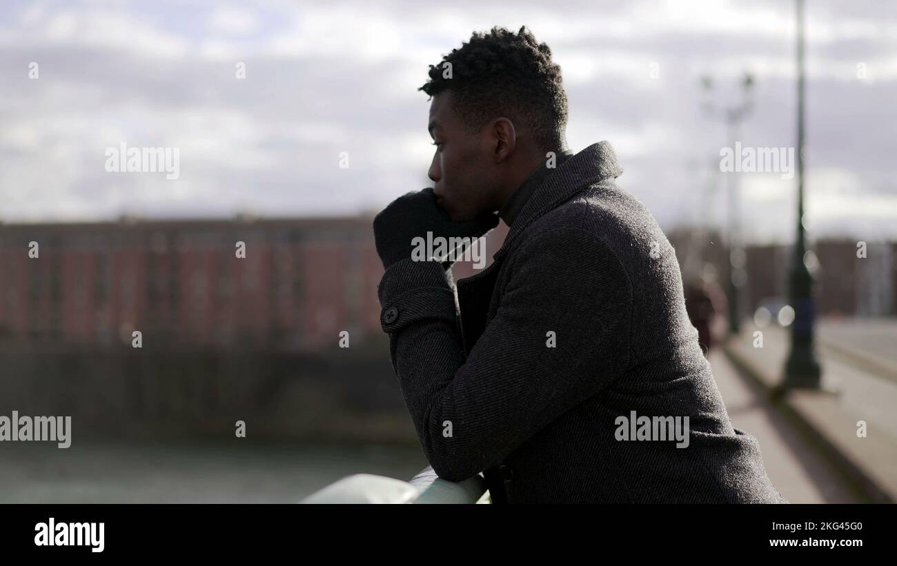 Pensive black African man standing by bridge thinking about life ...