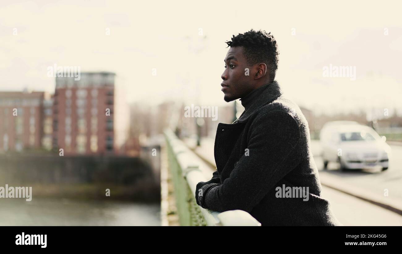 Pensive black African man standing by bridge thinking about life ...