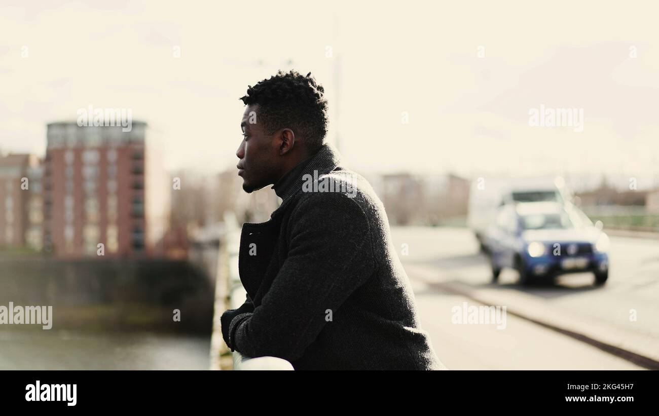 Pensive black African man standing by bridge thinking about life ...