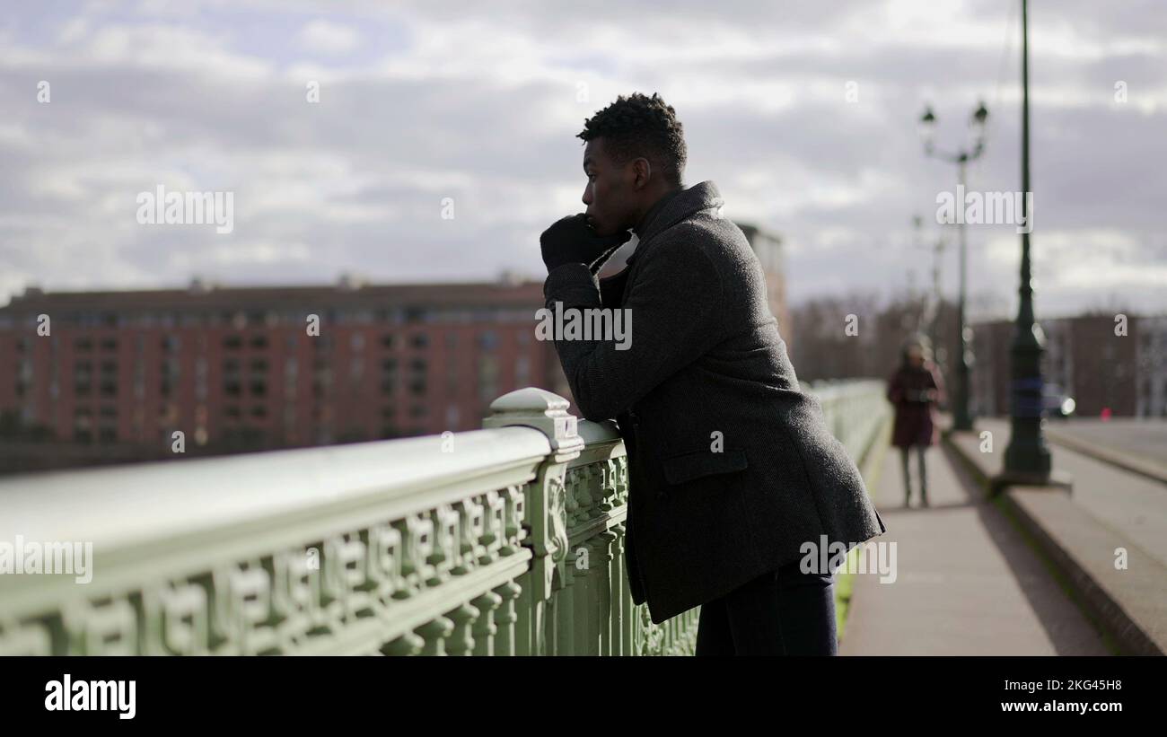 Pensive black African man standing by bridge thinking about life ...