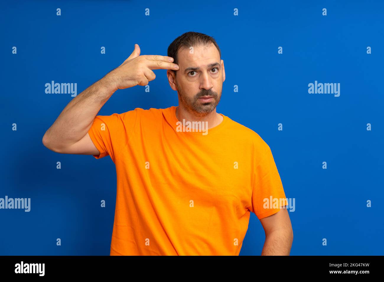 Headshot, kill me please. Depressed man with beard wearing orange T ...
