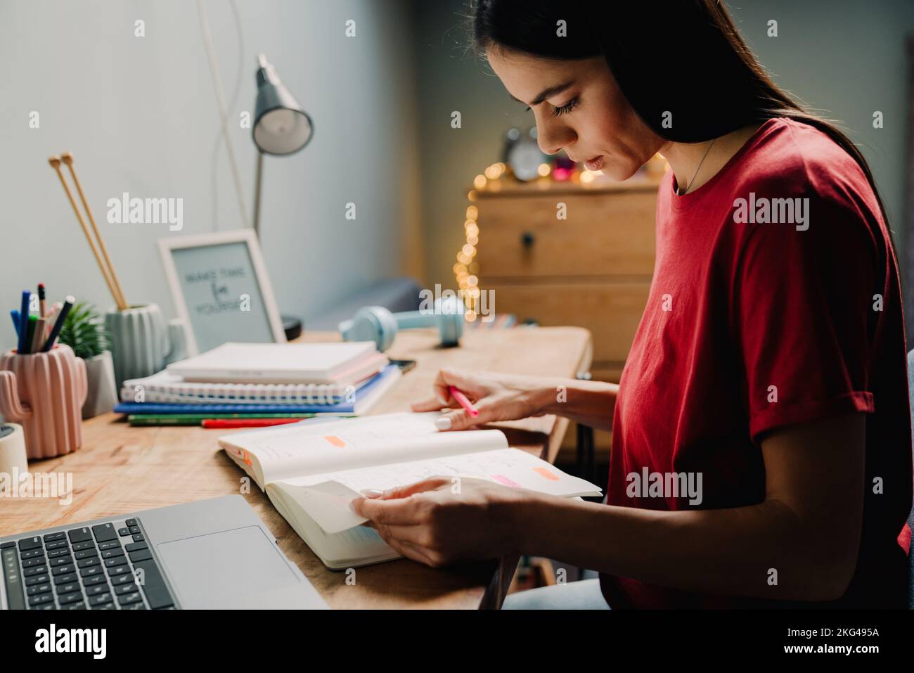 Young hispanic woman writing down notes at organizer while working on ...