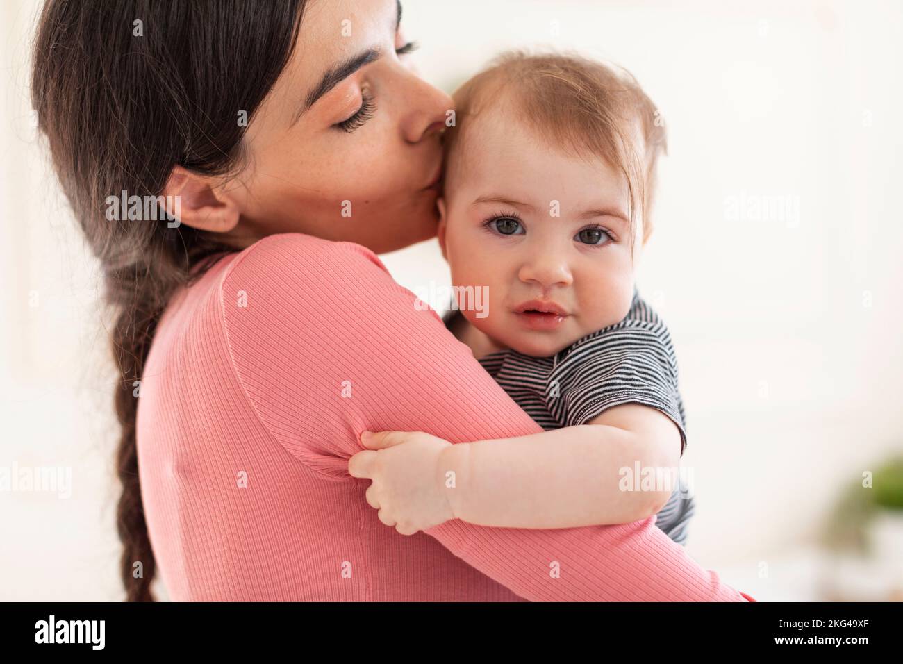 Caring young mother holding and kissing sweet little baby girl, mom and adorable kid bonding at ...