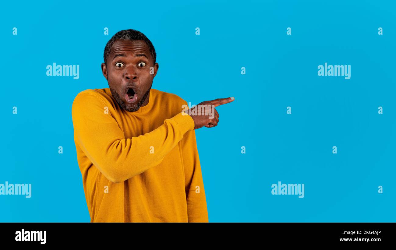 Shocked black man pointing at copy space isolated on blue Stock Photo ...