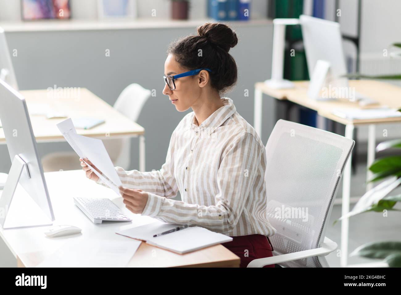 Focused businesswoman reading papers and business reports, sitting at ...