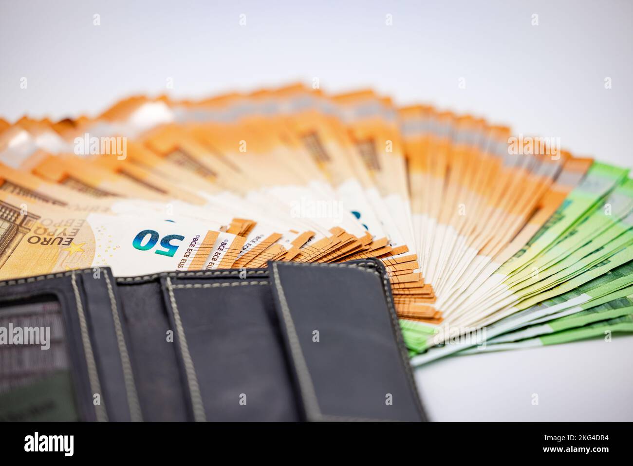 Close-up of euro banknotes in a fan with purse cropped against white ...