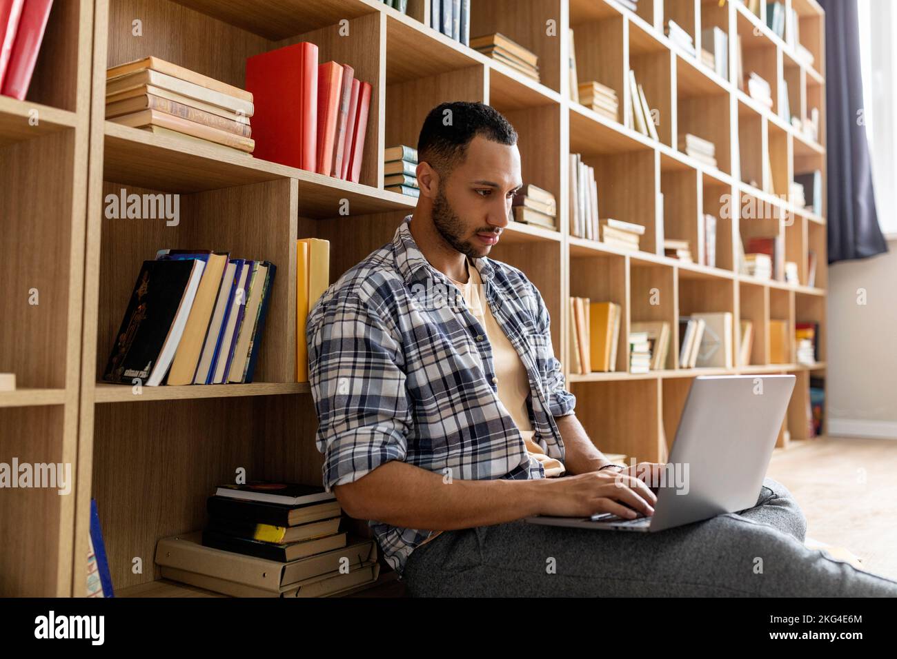 Young arab guy studying online from home, using laptop pc, sitting on ...