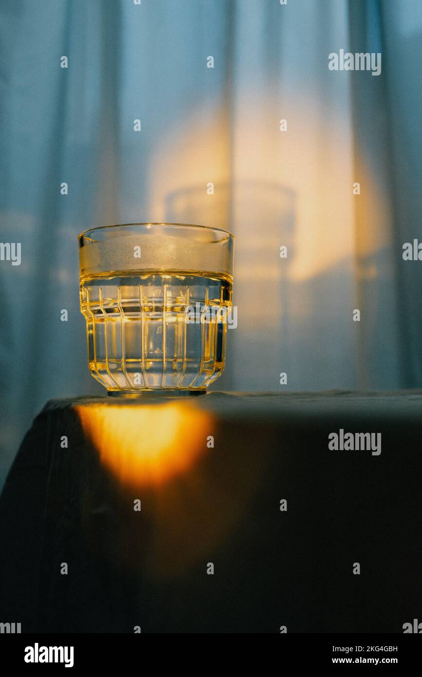 A vertical closeup shot of glass on the table and sun rays going ...