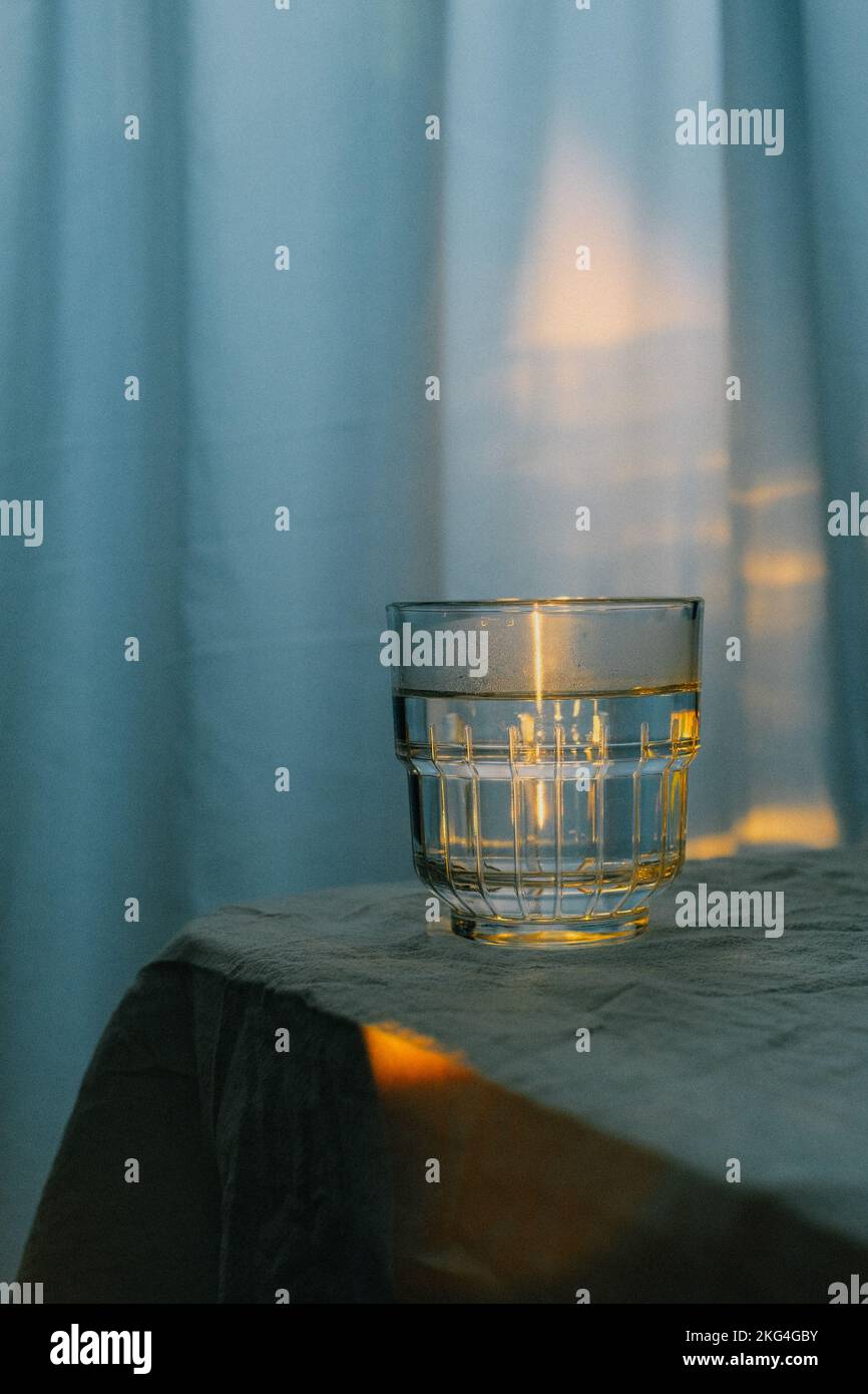 A vertical closeup shot of glass on the table and sun rays going ...