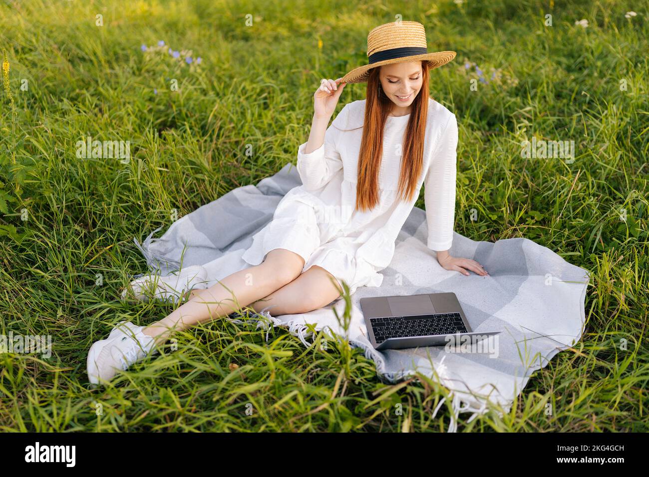 Happy smiling red-haired young woman wearing straw hat and white dress ...