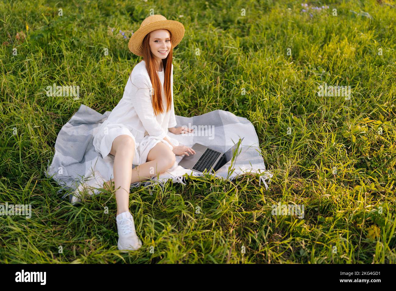 High-angle view of smiling young redhead woman wearing straw hat and ...