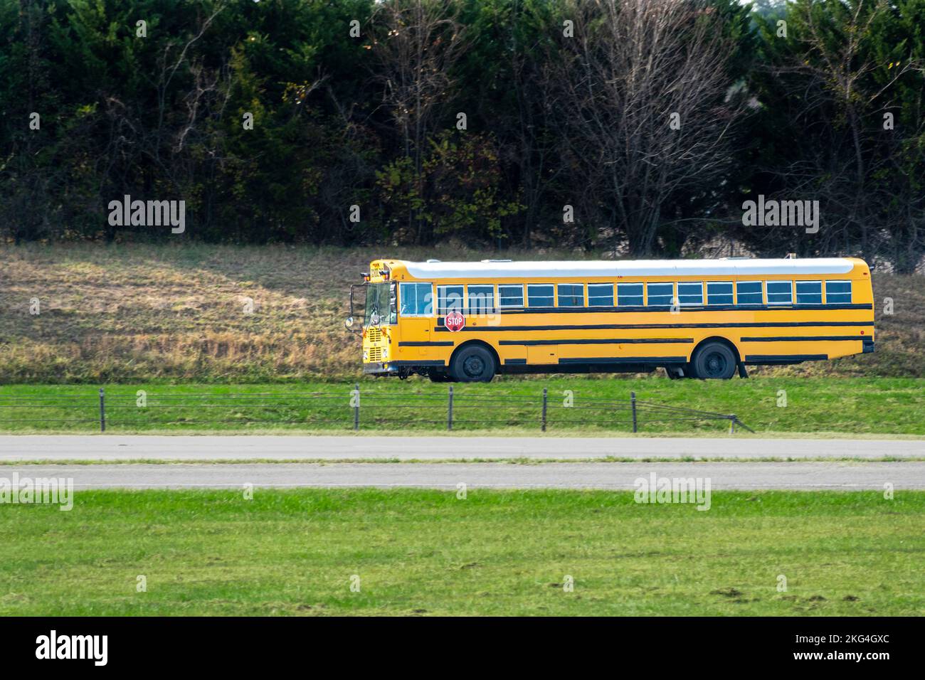 Horizontal shot of a long school bus on an empty road. Heat waves ...