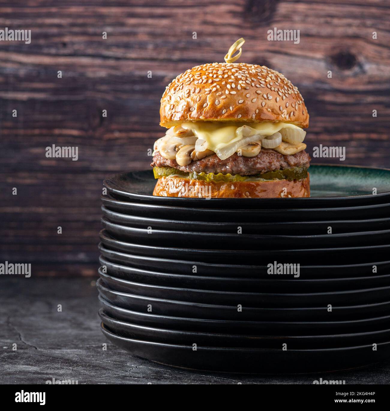 A close-up shot of a juicy burger placed on a several plates Stock ...