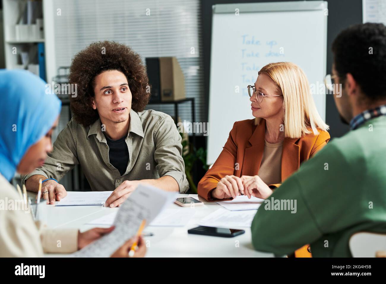Young confident multi-ethnic male student answering questions of other ...