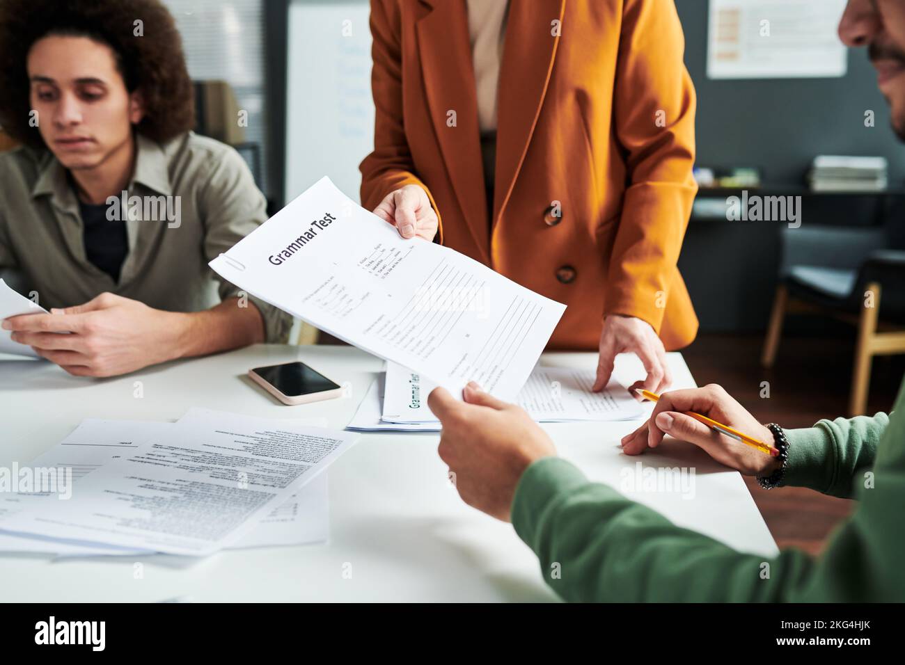 Document with English grammar test being passed by teacher to one of ...
