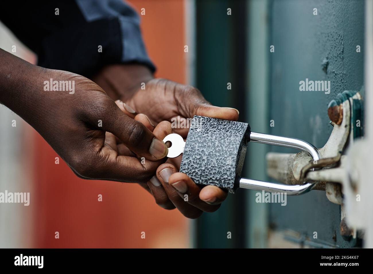 Close up of black man opening lock on container door in shipping docks ...