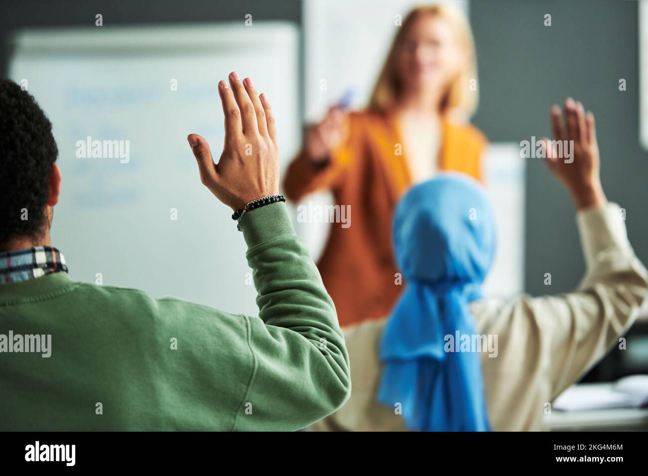 Raised hand of student working at seminar while sitting in front of ...