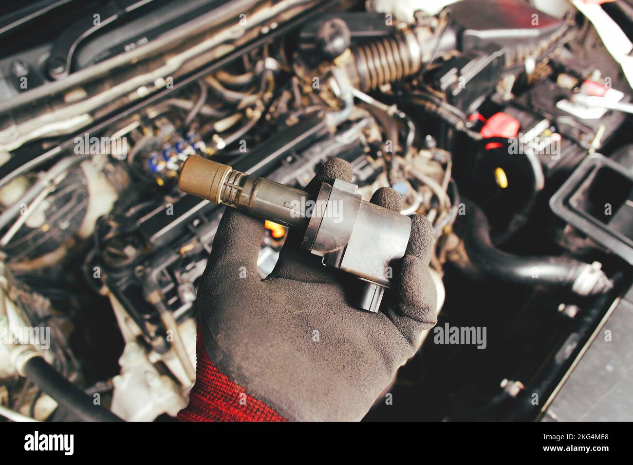 A mechanic hand holds an ignition coil for a spark plug in an ...