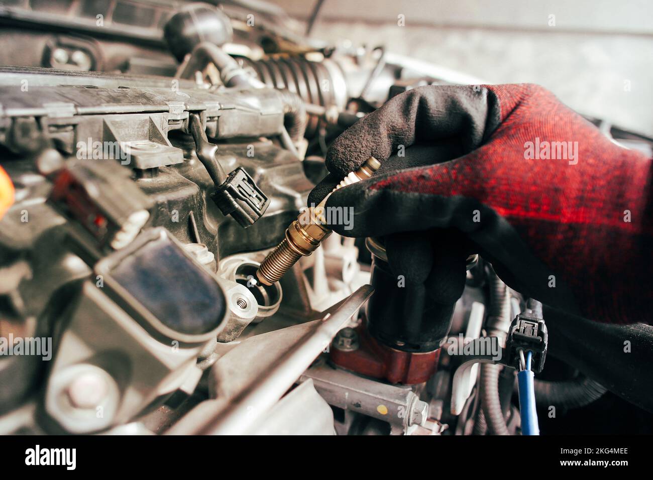A auto mechanic is installing automobile iridium spark plugs into the ...
