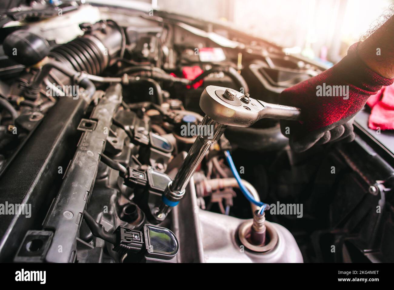 The red gloved hand of the auto mechanic is fastening the bolt with the ...