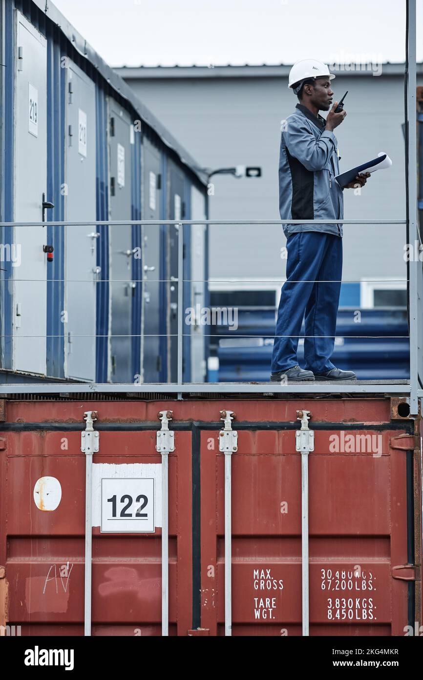 Graphic portrait of male worker standing on containers in shipping ...