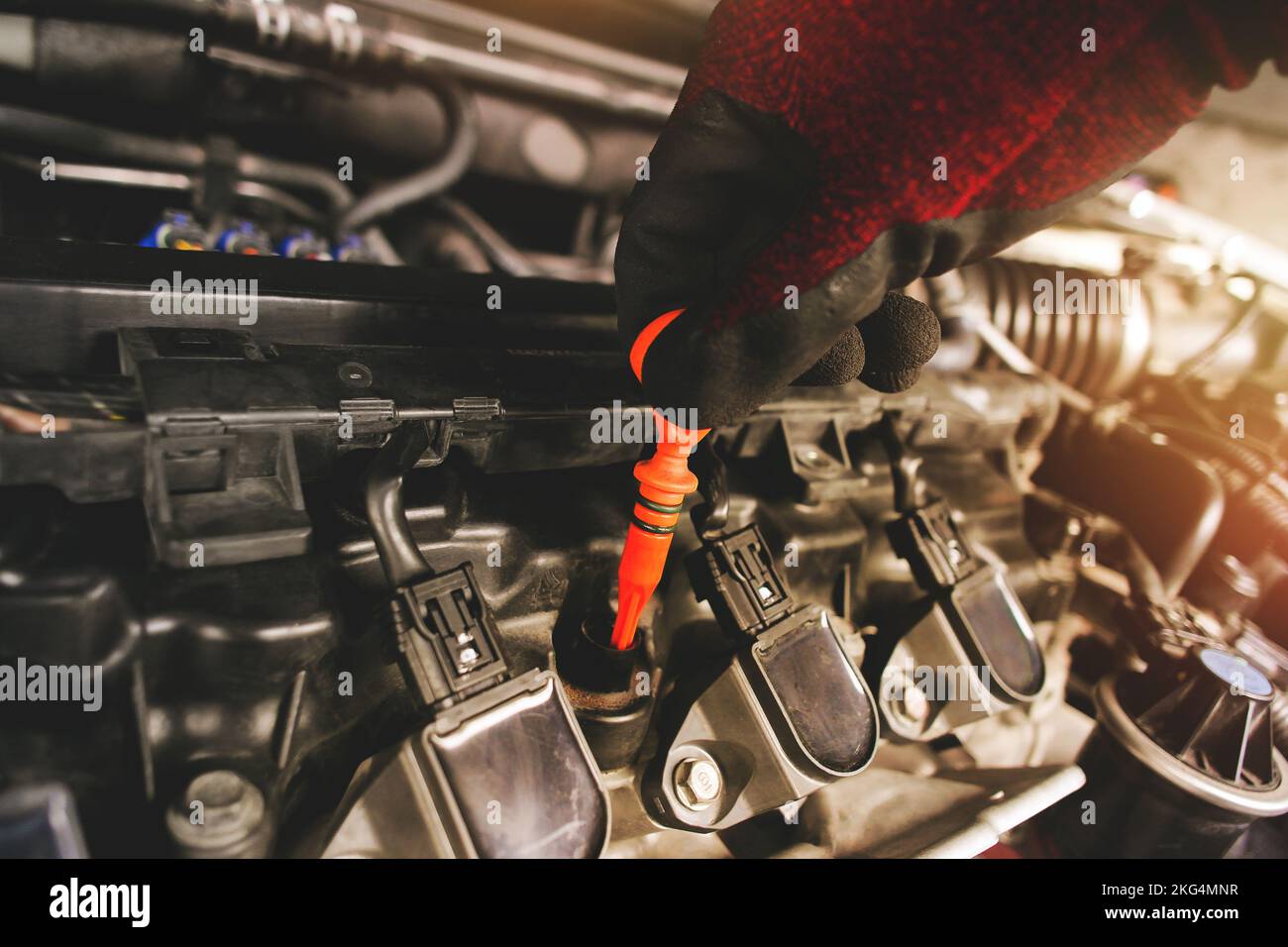 A mechanic is pulling the orange dipstick to check the oil level of the combustion engine in the ...