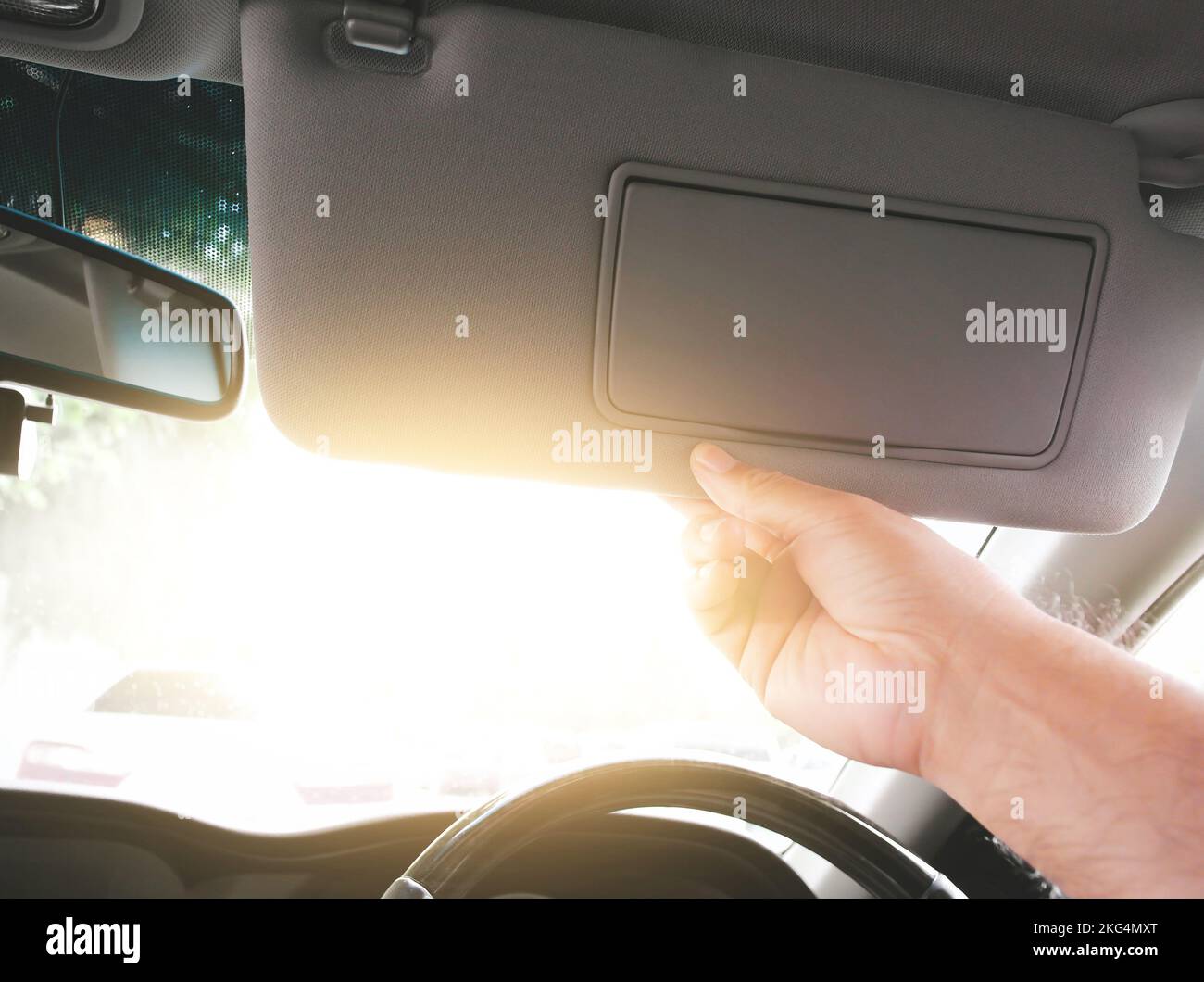 Driver manually adjusting the sun visor in order to block sunlight in a ...
