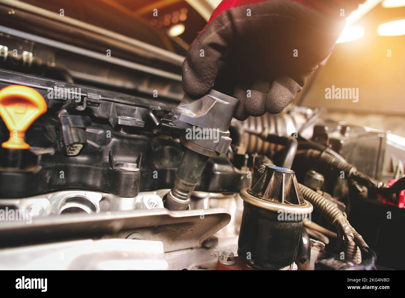 A auto mechanic is installing ignition coil for a spark plug into the ...