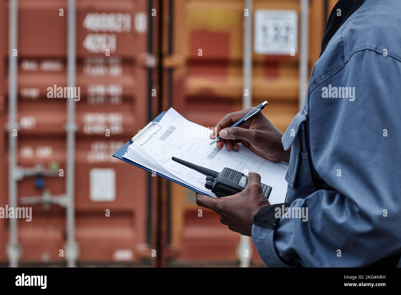 Close up of male worker wearing writing on clipboard in shipping docks ...