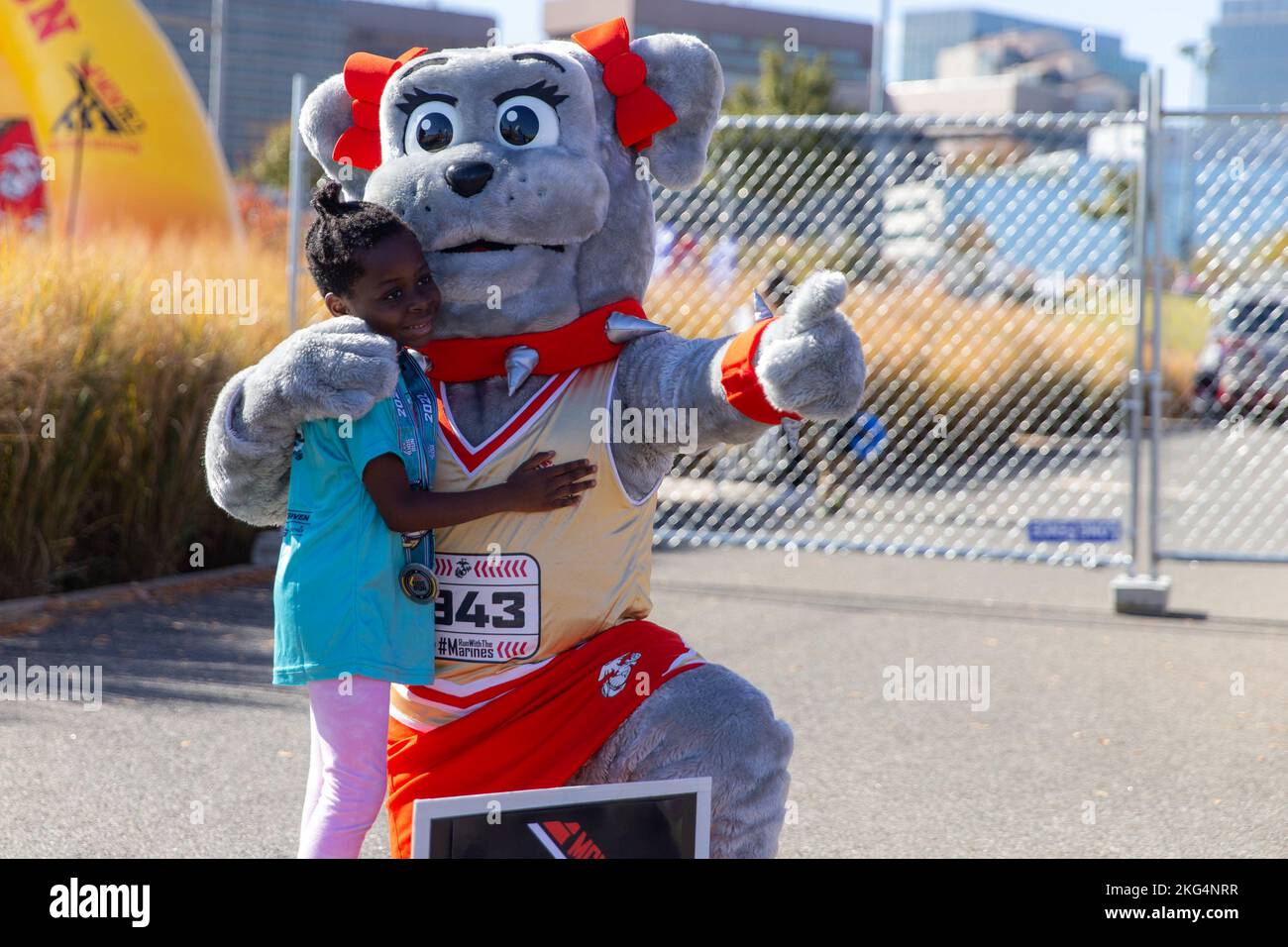 A child running the Marine Corps Marathon Kids Run interacts with Molly ...