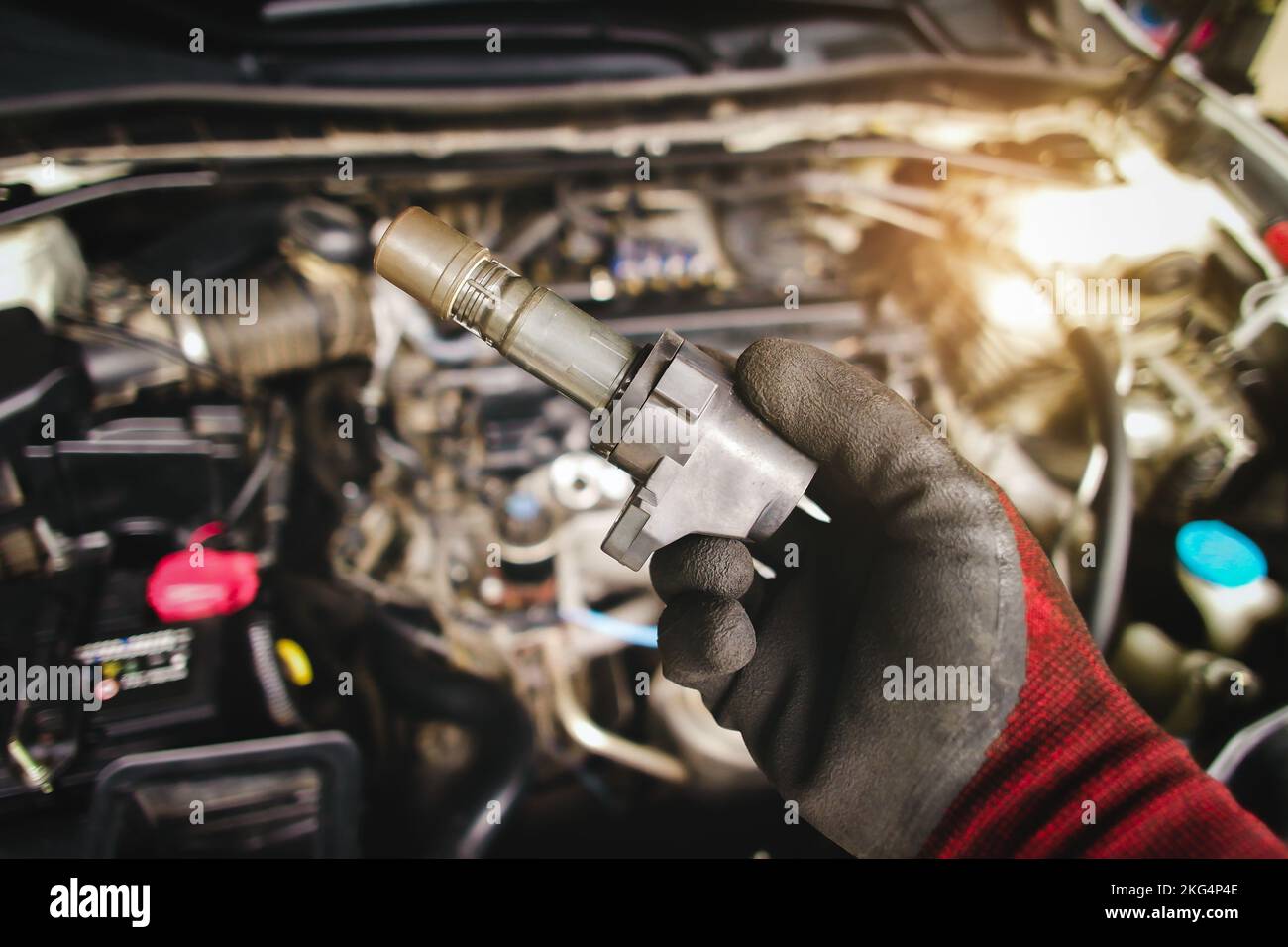 A mechanic hand holds an ignition coil for a spark plug in an ...