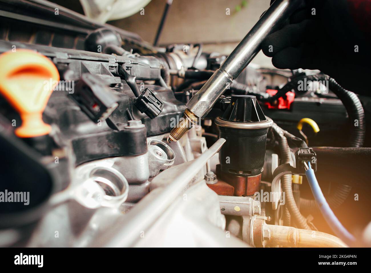 A auto mechanic is installing automobile iridium spark plugs into the ignition spark socket of ...