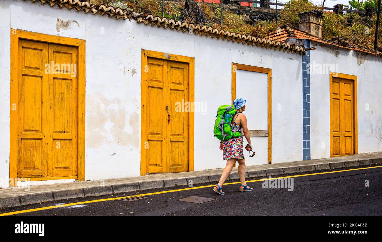 Lonely traveler walking by old stone buildings with brown-painted doors ...