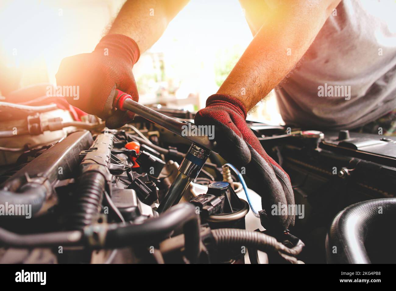 The red gloved hand of the auto mechanic is fastening the bolt with the ...