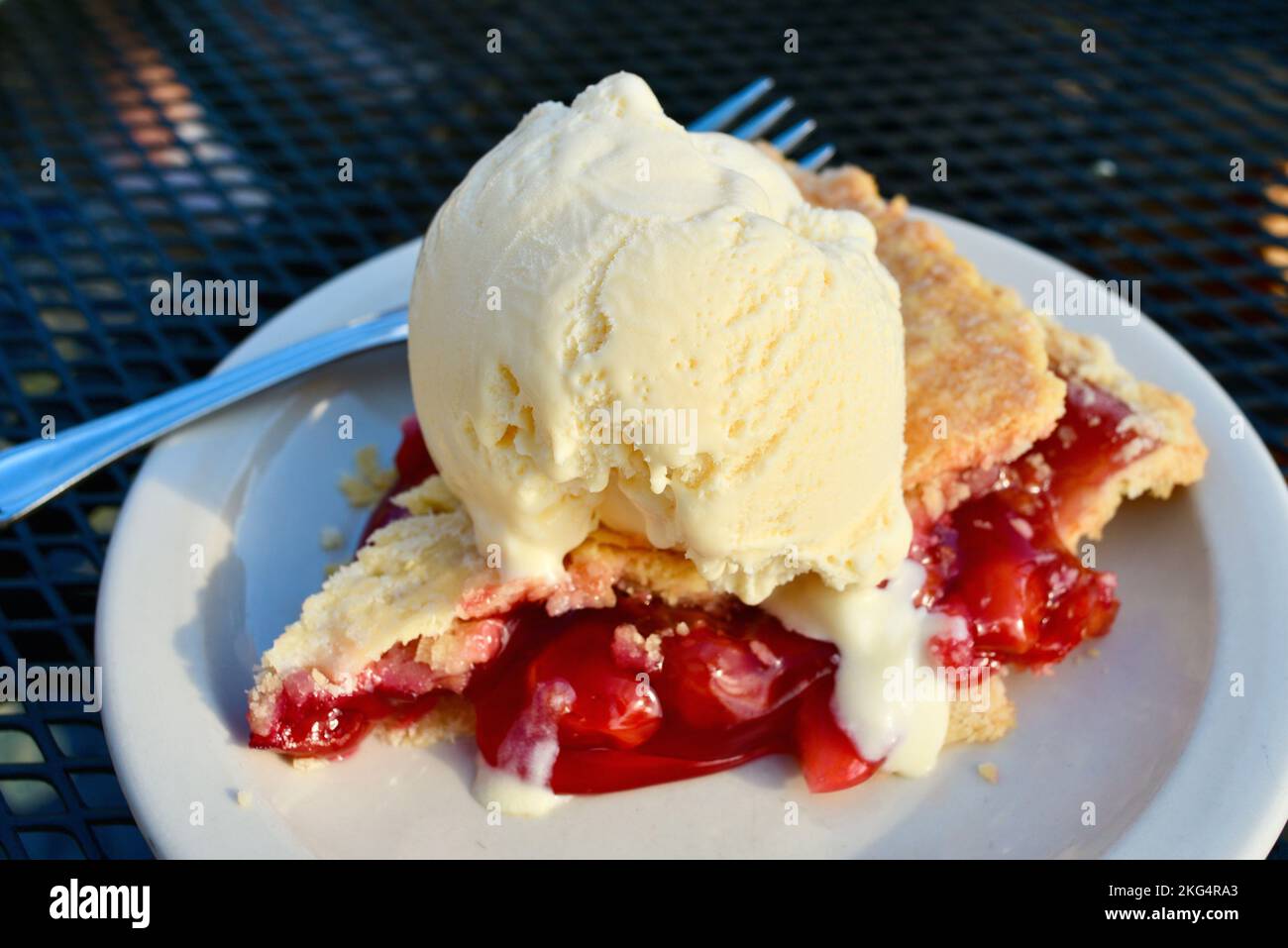 Piece of fresh baked cherry pie served a la mode with scoop of ice ...