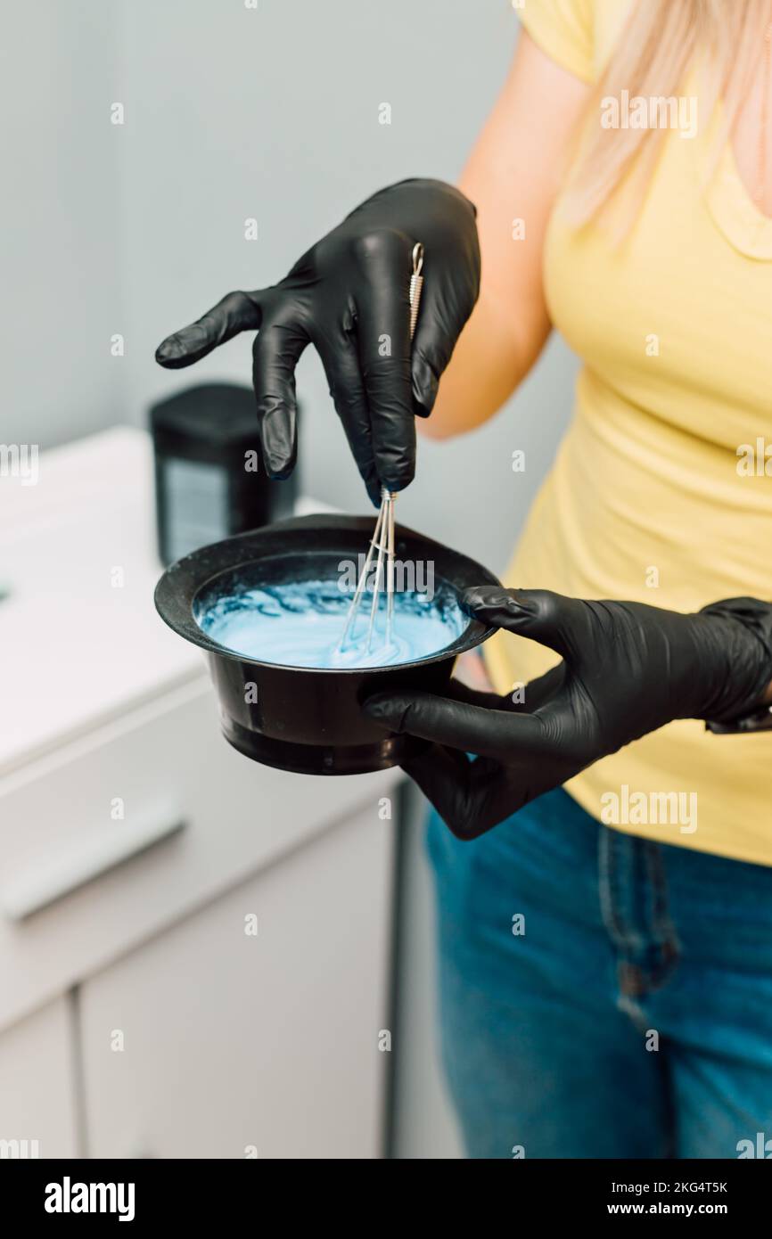 A professional hairdresser mixes a dye with an oxidizer. Hair coloring ...