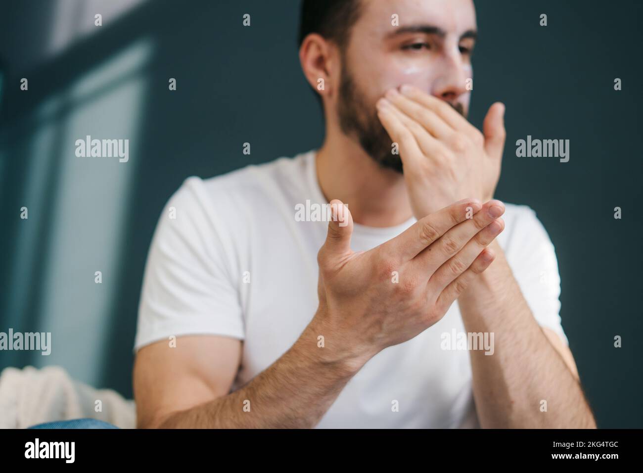 Handsome caucasian man applying moisturising cream on face while ...