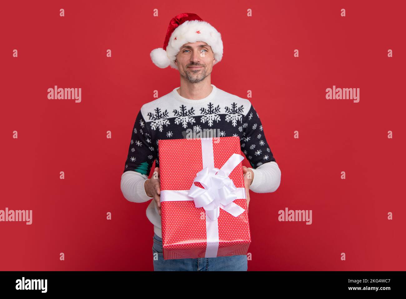 Optimistic man in Santa hat and winter sweater smiling and holding ...