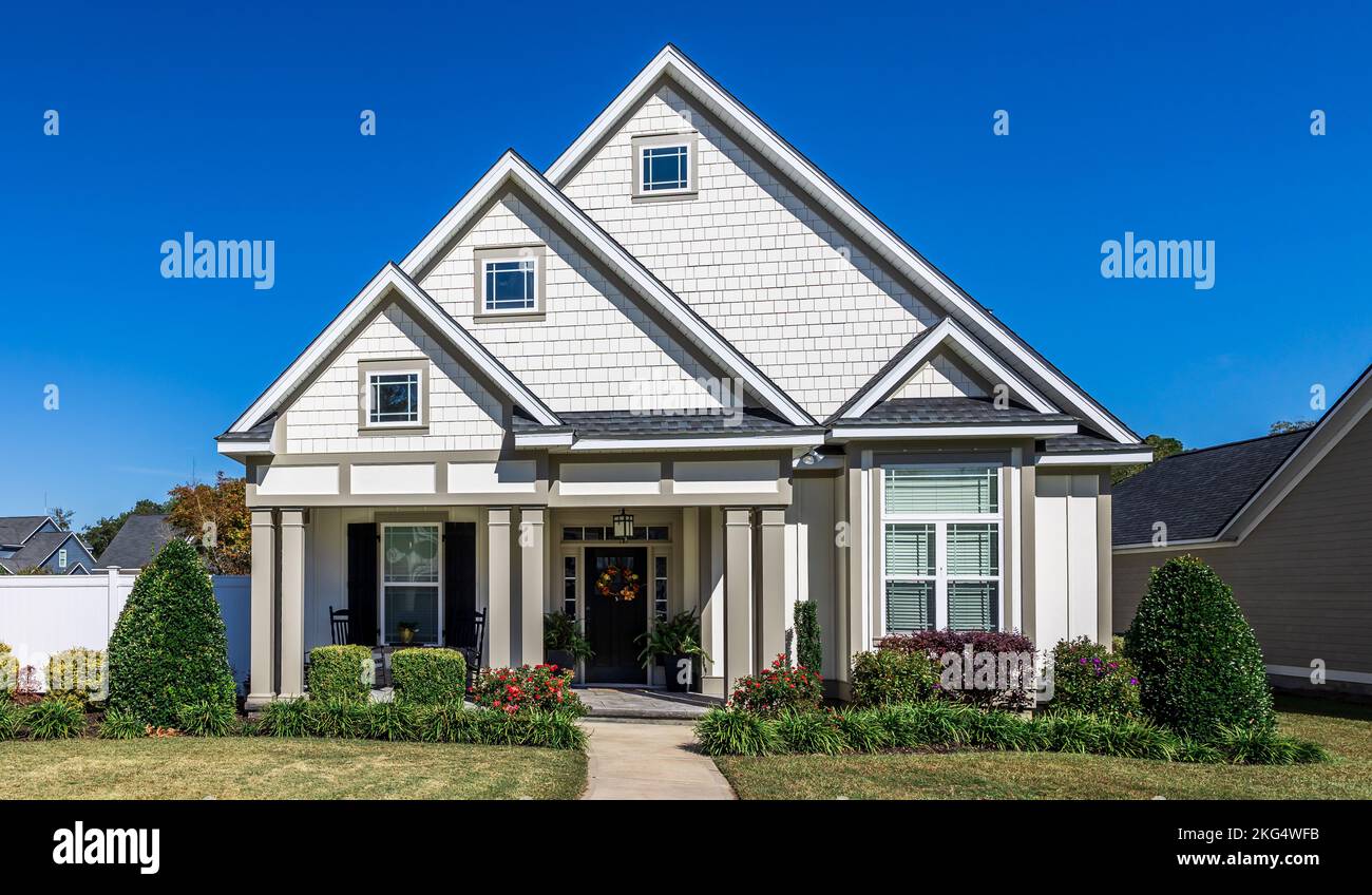 The front view of a cottage craftsman style white house with a triple ...