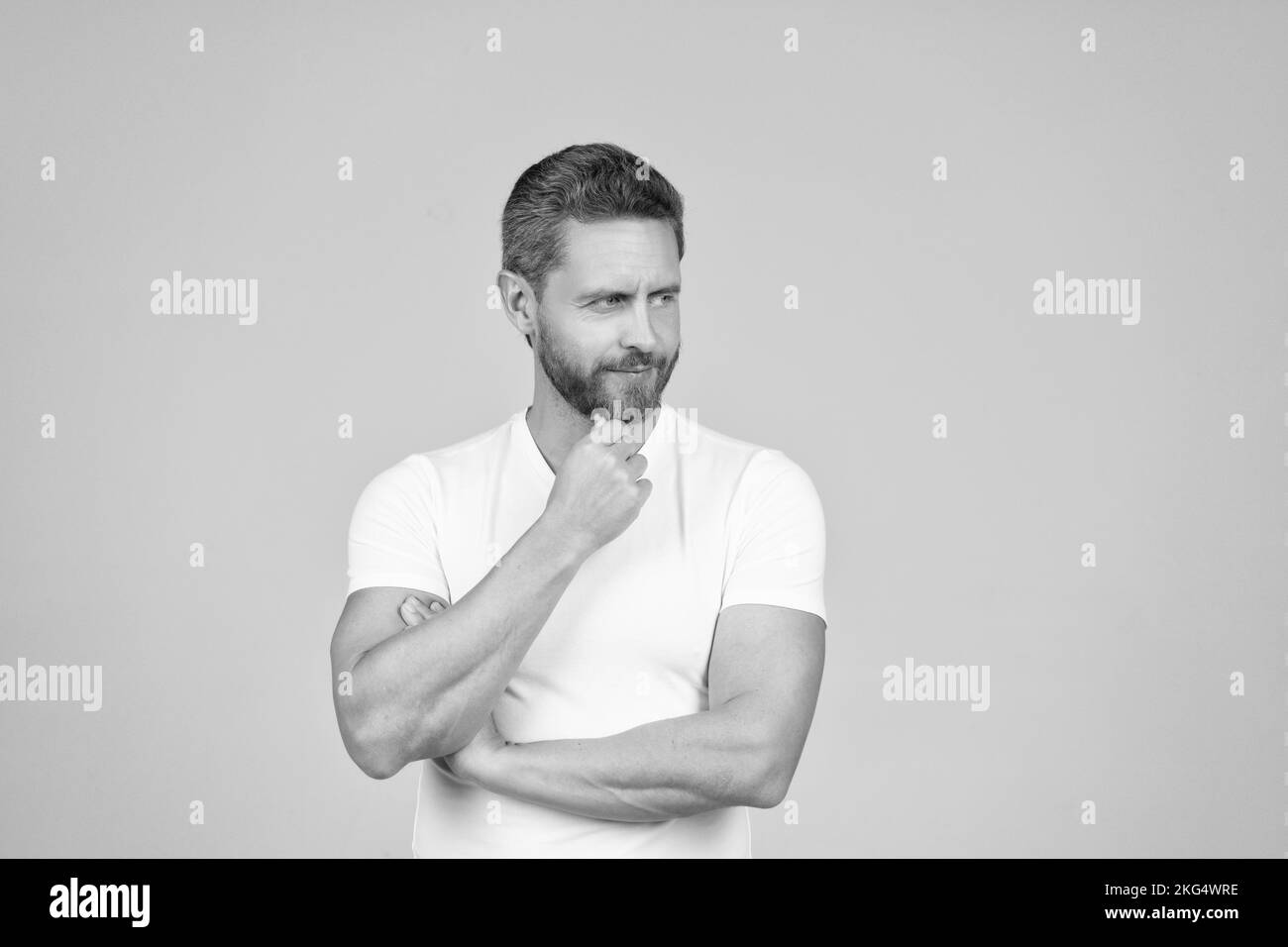 Serious thoughtful man in white tshirt stroke chin thinking grey ...