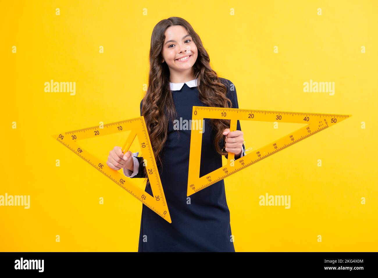 Back to school. School girl hold ruler measuring isolated on yellow ...