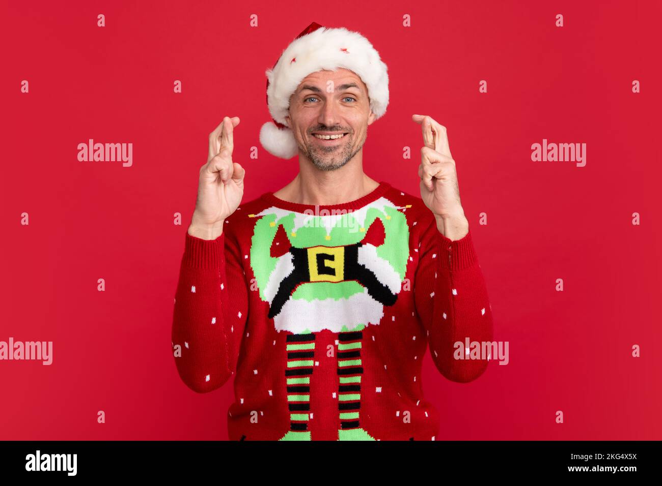 Good luck. Man in holiday sweater and Santa hat on studio background ...