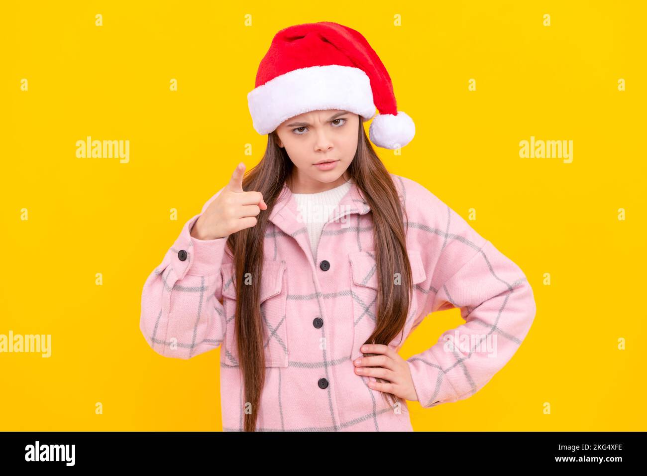 strict child in santa claus hat point finger on yellow background ...